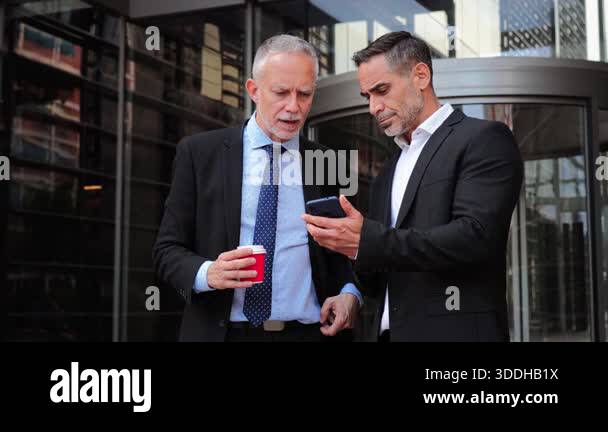 Two professional businessmen engaged in a serious conversation while ...