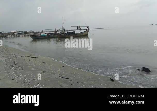 A small traditional fishing boat floats calmly on the open sea under a ...