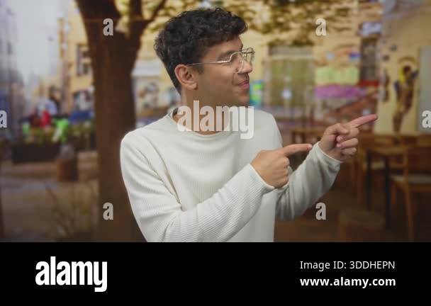 Man pointing both index fingers to the right on building terrace with ...