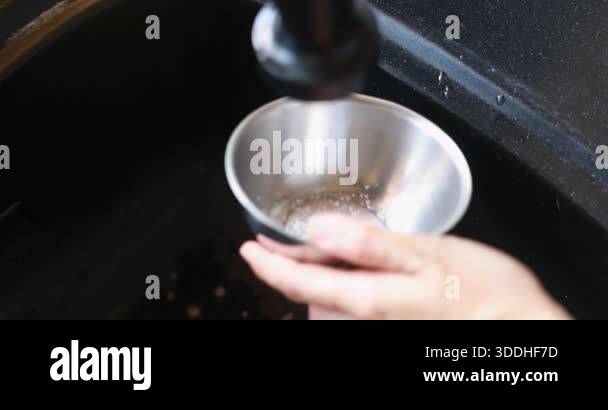 Close up hands washing stainless steel bowl under running water from ...