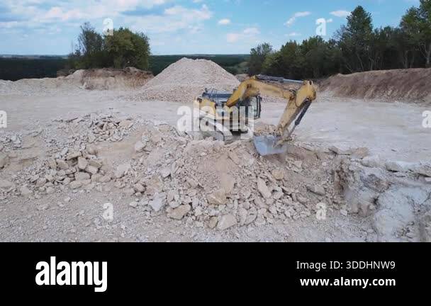 Footage of yellow moving crawler excavator loading bucket with stones ...