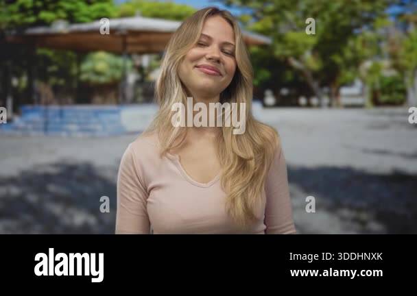 Woman with flowing blonde hair flips middle finger in park under ...