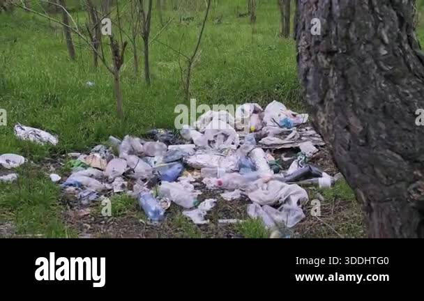 A large heap of plastic bottles and white waste lies on the grass near ...