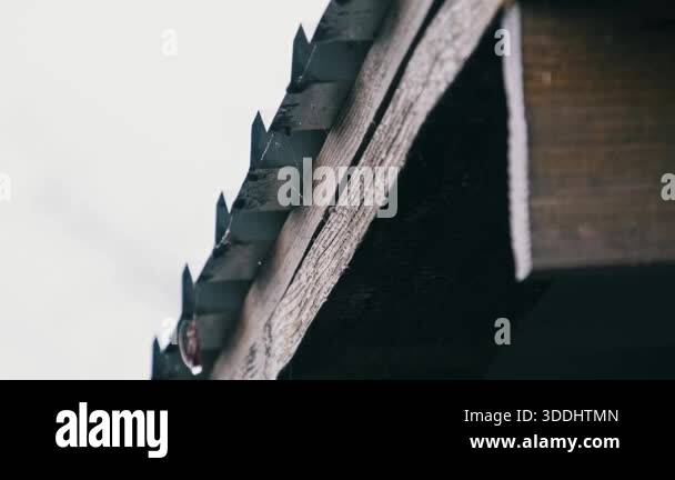 Water droplets drip rhythmically from the edge of a corrugated metal ...
