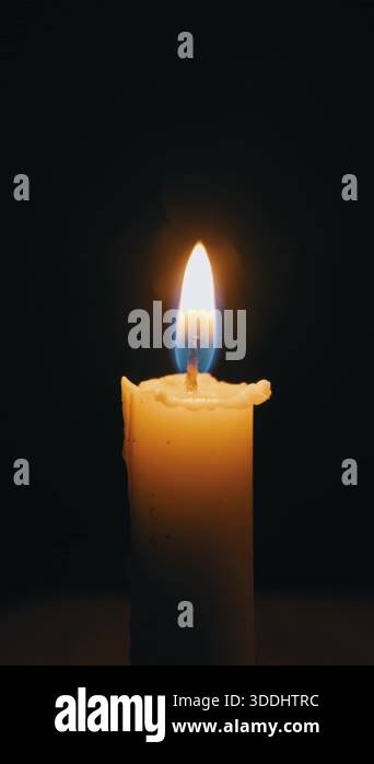 Hand lights a candle wick with a burning match stick against a black ...