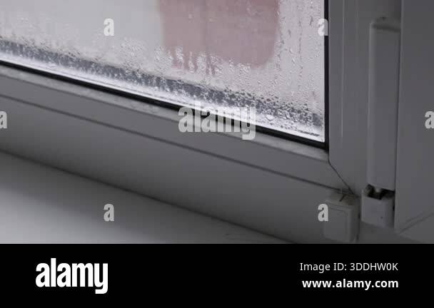 Heavy condensation with water droplets forms on a cold glass window ...