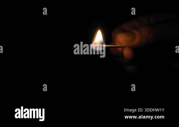 Male hand strikes a wooden matchstick, holding it as the flame ignites ...
