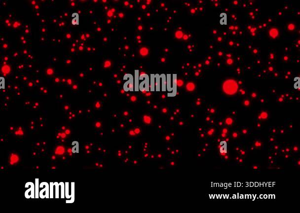 Abstract red dot particles drift aimlessly against a black background ...