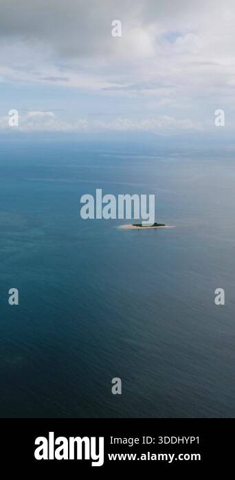 View of small island near green coastline surrounded by calm blue sea ...
