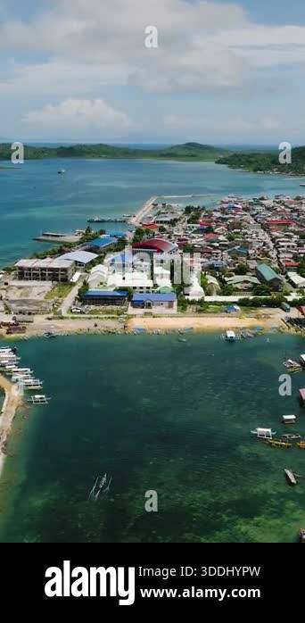 Cluster of colorful coastal houses along shallow turquoise sea. Siargao ...