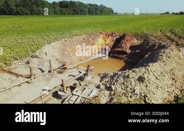Pipeline construction with pit filled with substance near oil refinery ...