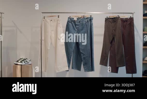 A variety of pants and shoes displayed in a clothing store. White cargo ...
