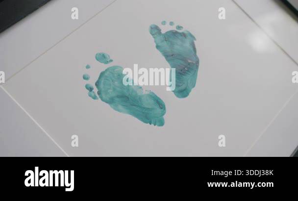 Closeup of green imprints of baby feet on white background paper ...