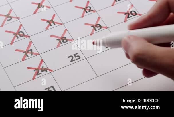 Close-up of a person crossing out days on a calendar, indicating a ...