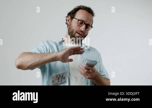 Man in glasses throwing money in the air in slow motion. He holds a ...