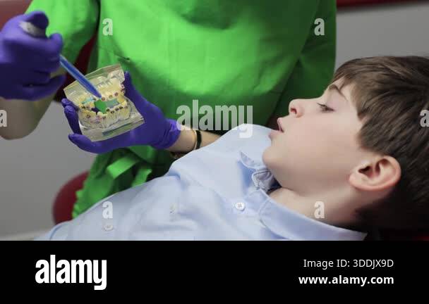 Professional Orthodontist Teaching A Young Boy How To Clean His Teeth