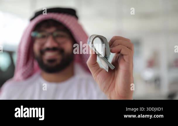 Wealthy emirati man in traditional dress showing off a wad of cash ...