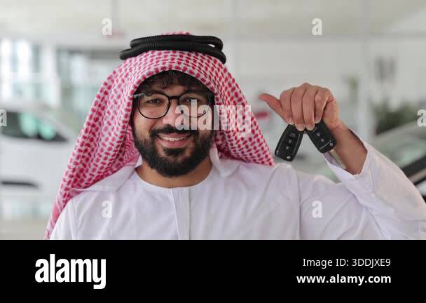 Smiling middle eastern man in traditional clothing holding keys to a ...