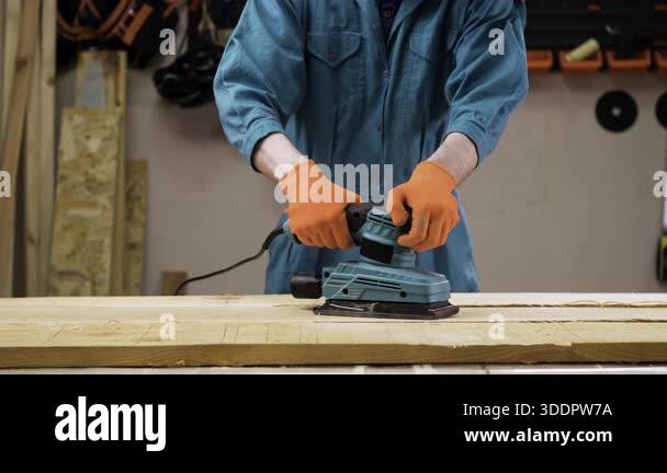 Carpenter sanding wooden board with electric orbital sander in his ...