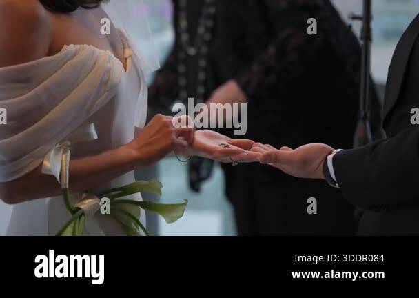 Hands Exchanging Rings At Ceremony, Officiant In Background, Bride ...