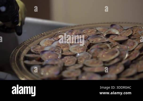 Gloved Hands Plating Abalone Shells On Ornate Tray, CloseUp In Warm ...