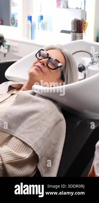 Elegant older woman with grey hair and glasses relaxing with her eyes ...