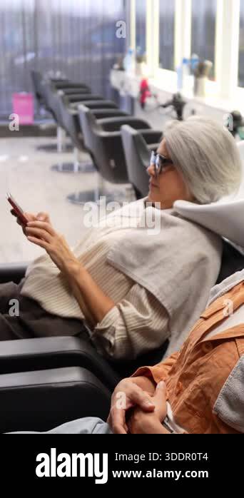 Senior woman with gray hair and glasses using a mobile phone while ...