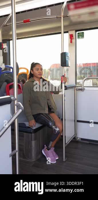 Beautiful young woman with a prosthetic leg standing up from her seat ...