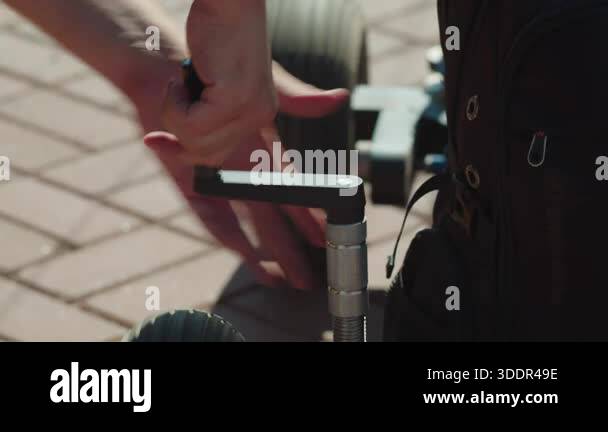 Assistant rotates metal crank assembling camera stand with steady ...