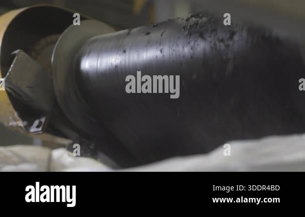 Industrial conveyor drops shredded rubber fragments into container ...
