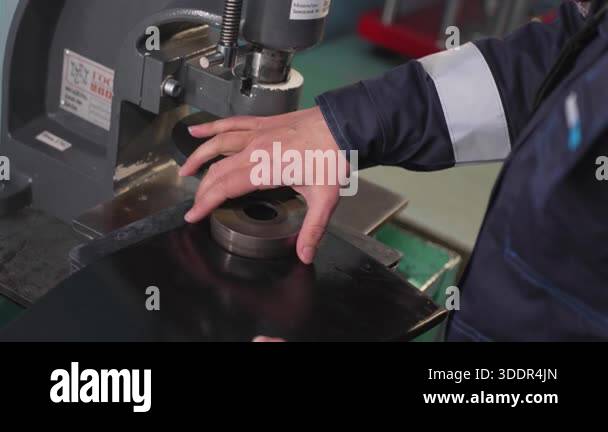 Worker removes metal mold from press and inspects rubber part ...