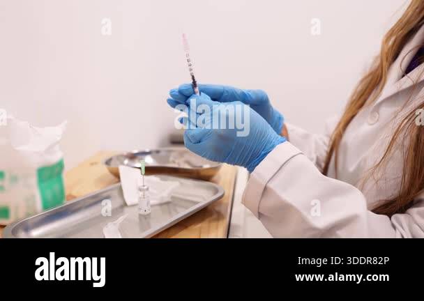Unrecognizable doctor in a white lab coat and blue gloves preparing a ...