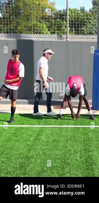 Young multicultural football players warming up with their coach ...