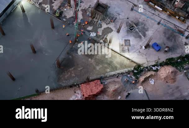 Aerial view of workers pouring concrete for a large building slab at ...