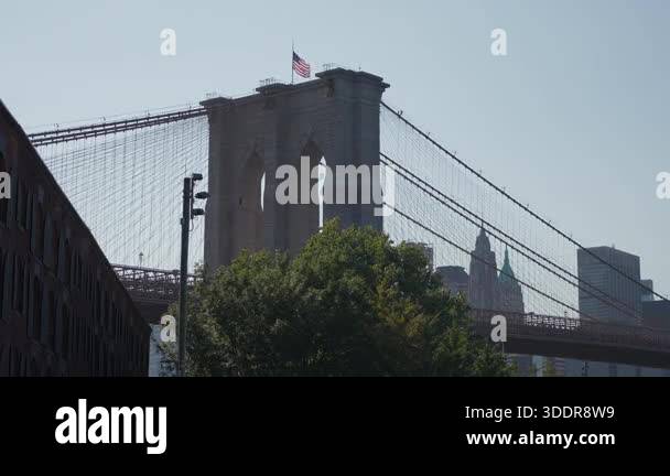 Brooklyn Bridge Tower With Waving Flag And TreeLined Riverbank, Soft ...