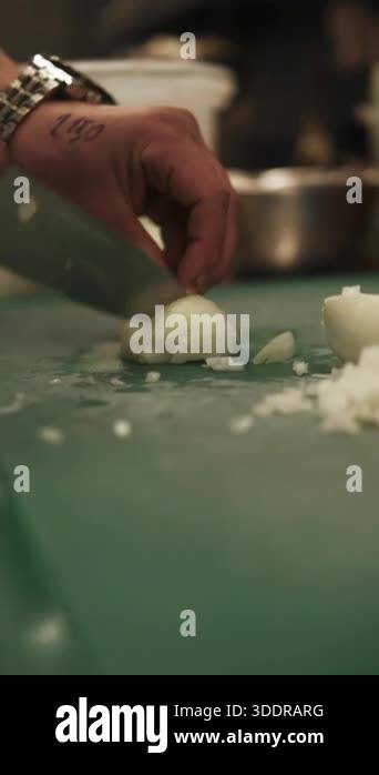 Vertical video. Chopping onion. Vegetable slicing. Restaurant chef hand ...
