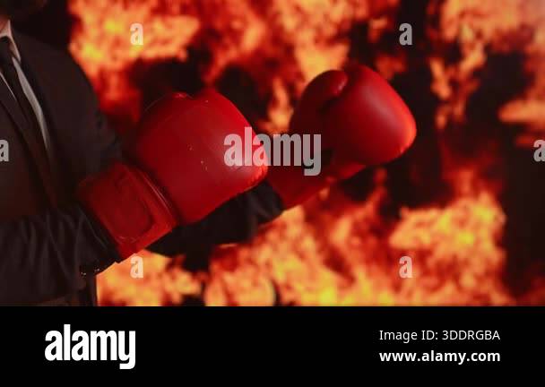 A determined businessman wearing a suit and red boxing gloves stands in ...