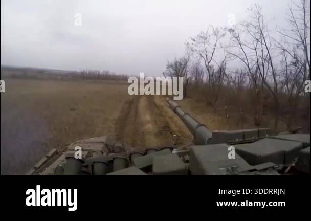An armored battle tank drives backwards, fire flashes from explosions ...