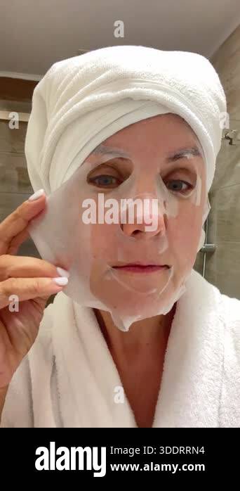 A woman straightens a cloth care mask on her face. Facial skin care ...