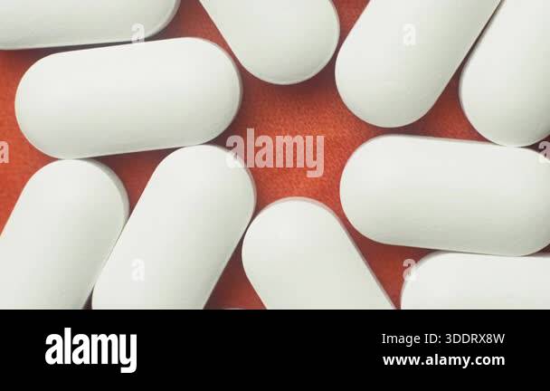 White tablets lying on a bright orange surface, highlighting their ...