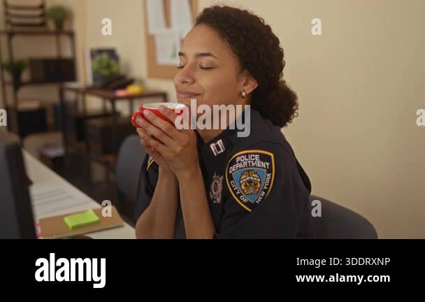 Woman in police uniform enjoying coffee at desk in a police station ...