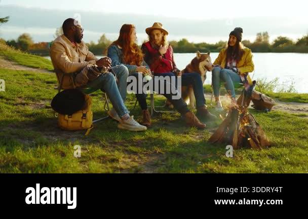 In nature stylish friends sitting near campfire in nature. Young people ...