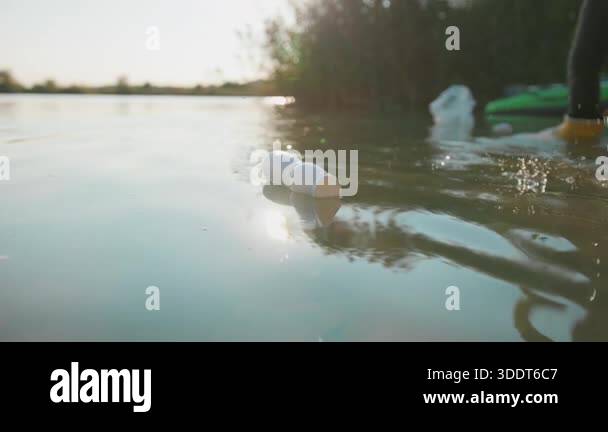 Closeup of polluted river water with plastic rubbish. Young boy walking ...