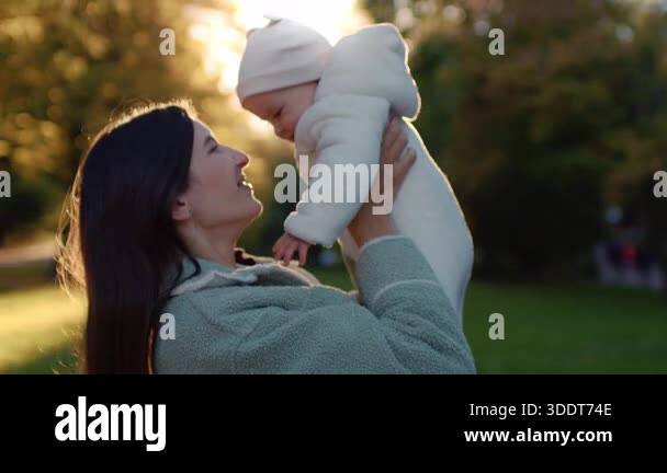 Footage of happy mother holding baby in nice soft white clothes while ...