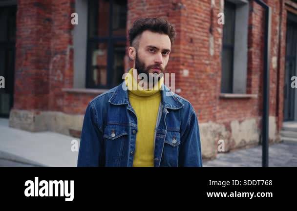 Serious Caucasian guy with stylish haircut standing on street, looking ...