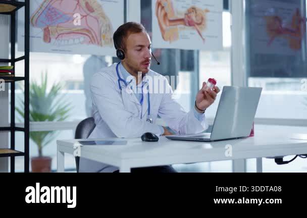 Young man doctor in white medical coat with headphones making ...