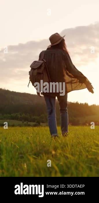 A traveler enjoys a peaceful walk in a vibrant field at sunset ...