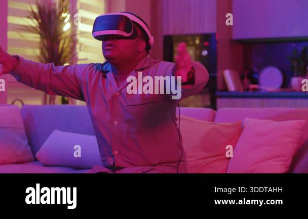 Funny mixed race young man wearing virtual reality headset sitting at ...