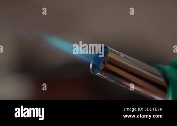 Butane torch with flame, close-up on blurred background. Turning off ...