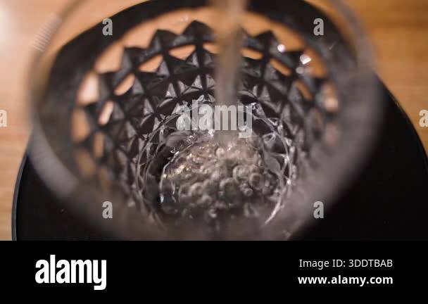 Water is poured into a transparent glass, close-up in slow motion. High ...